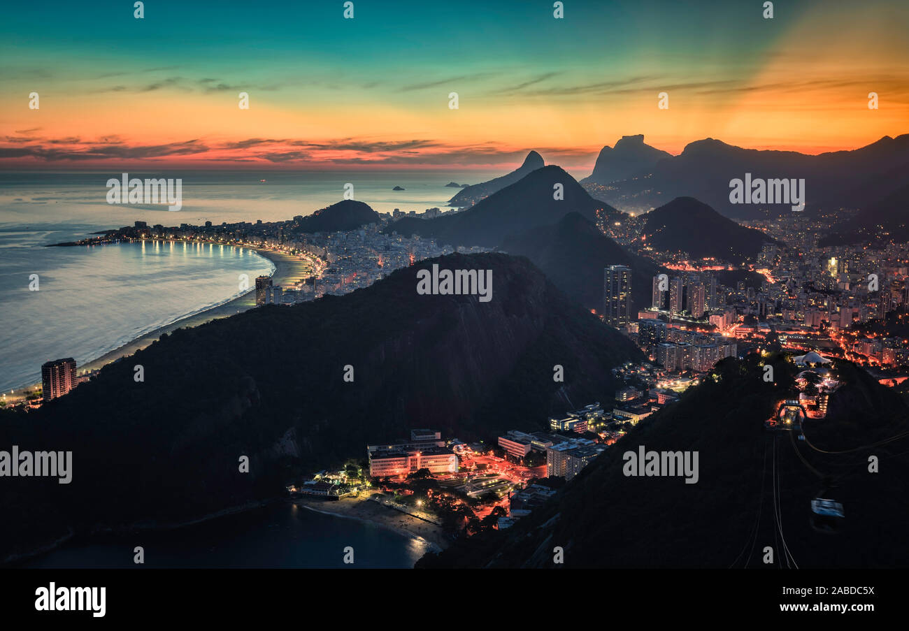 Sunset behind the mountains with iluminated Rio de Janeiro and ...