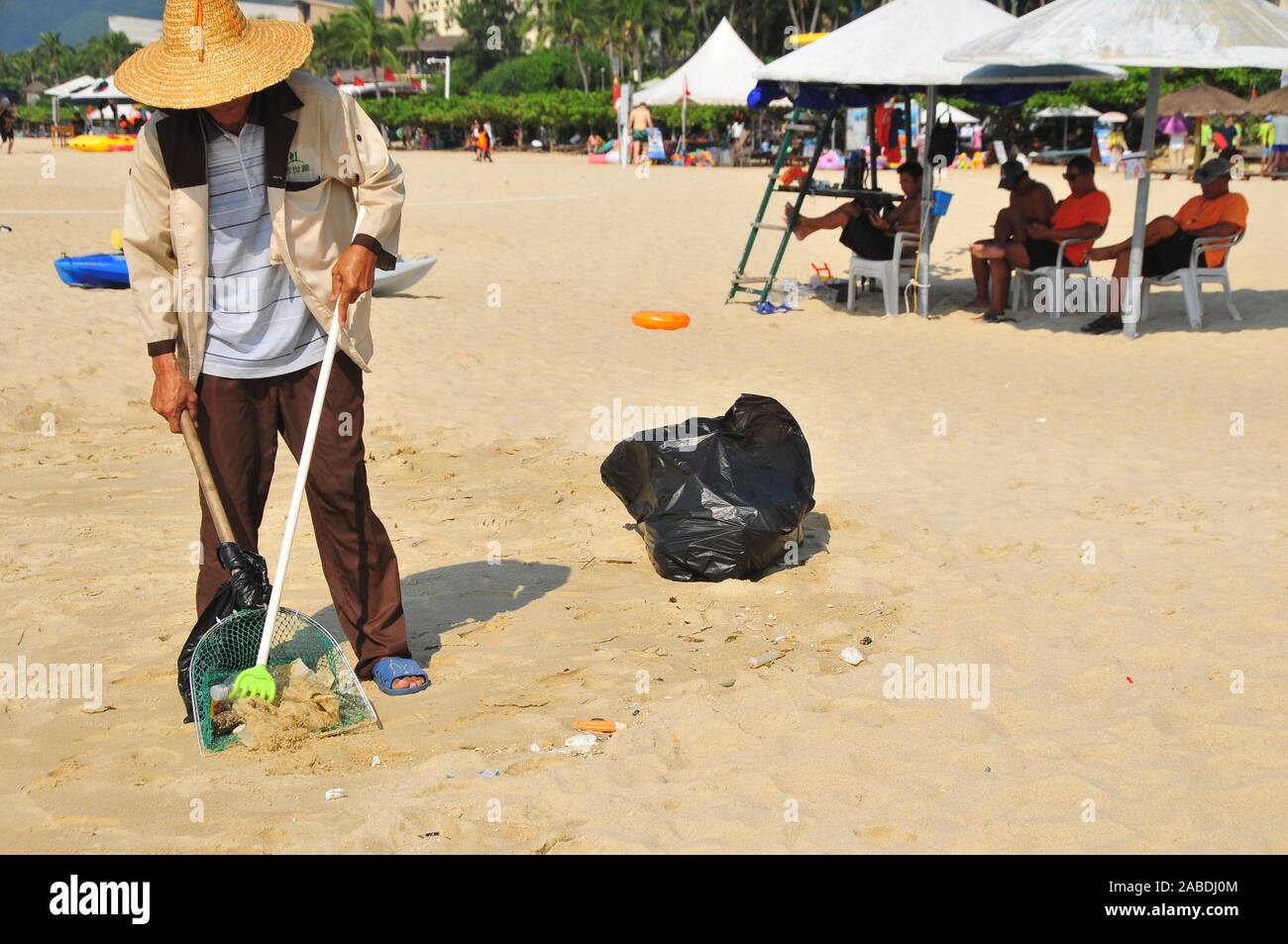 A person picks up garbage left by tourists near the beach of Yalong Bay ...
