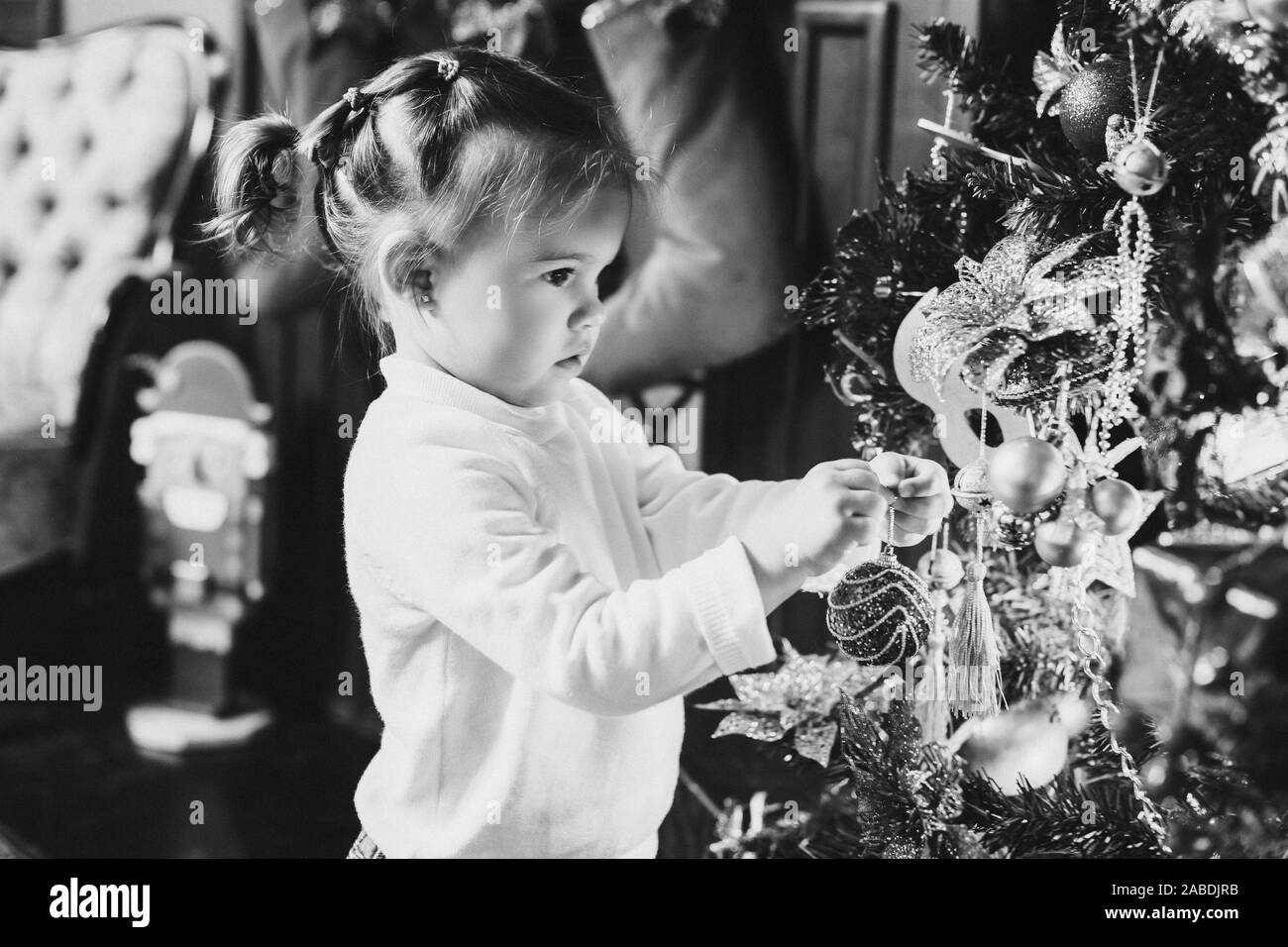 Cute little girl with Christmas tree. Side view of adorable little girl ...