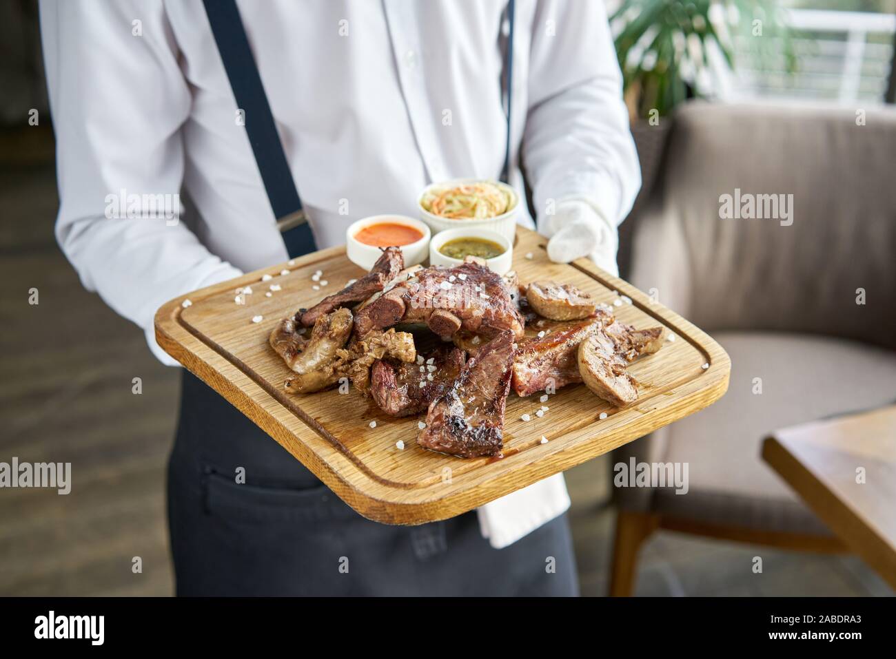 The waiter is holding a plate Various grilled meat set with Pickled ...