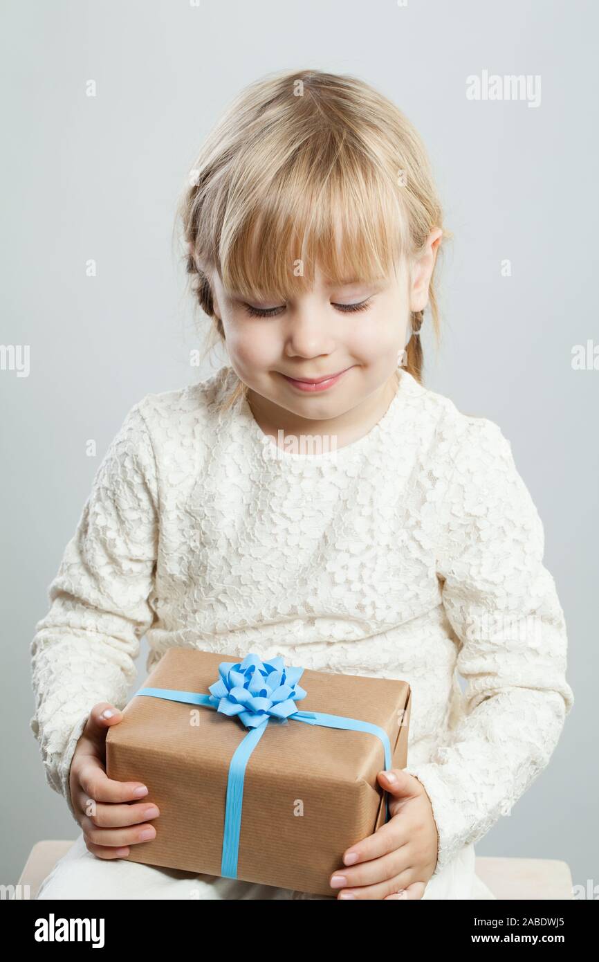 Cute little girl holding a gift box. child smiling wonders what is ...