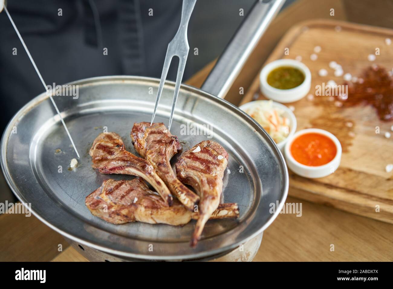The waiter is butchering with a knife. Rack of lamb , grilled meat with ...