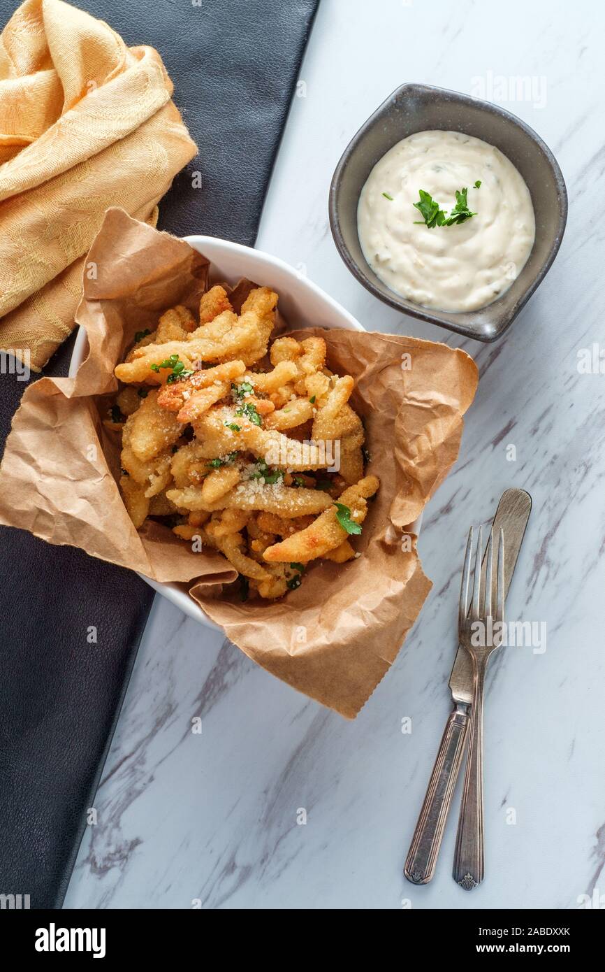 New England fried clam strips served with a bowl of tartar dipping ...