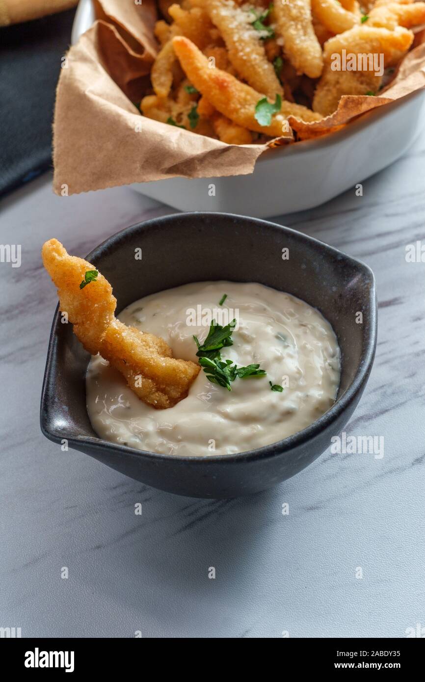 New England fried clam strips served with a bowl of tartar dipping ...