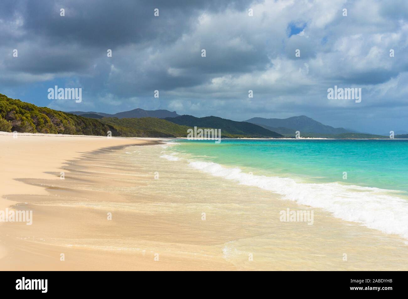 Beautiful tropical beach with mild waves and white sea foam on sandy ...