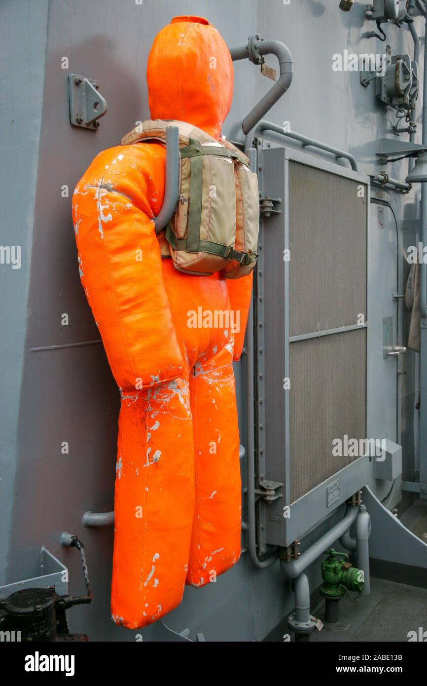 A training mannequin hangs on the wall of a warship. Orange doll with a ...