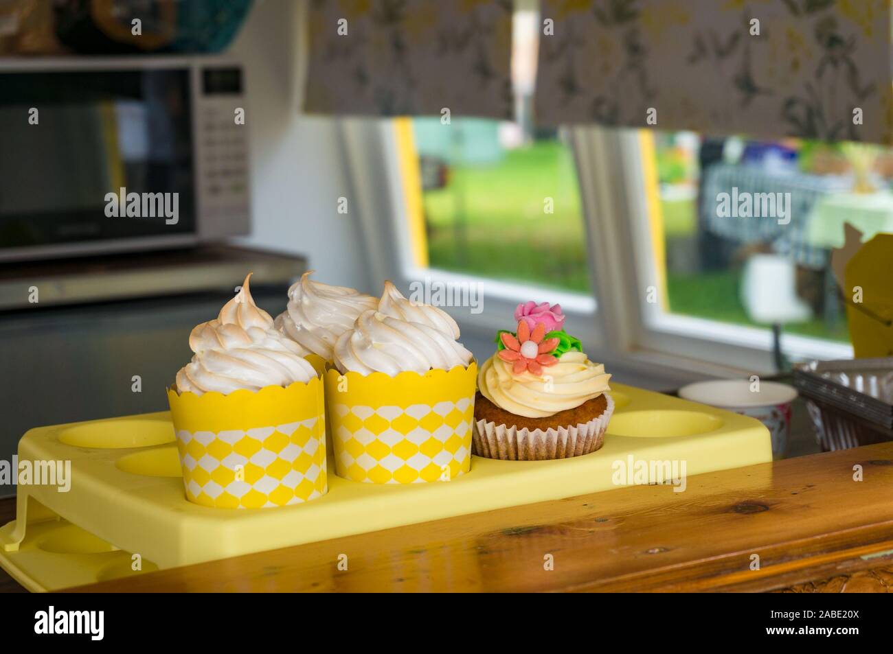 Bright yellow meringue cupcakes at display on counter top. Food ...