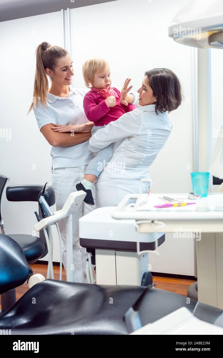 Dentist and her assistant with child in the office Stock Photo - Alamy