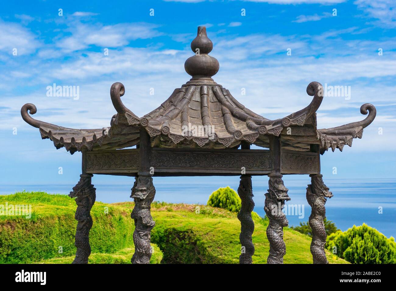 Ornated roof of asian-style pavilion, alcove with sea and grass on the ...