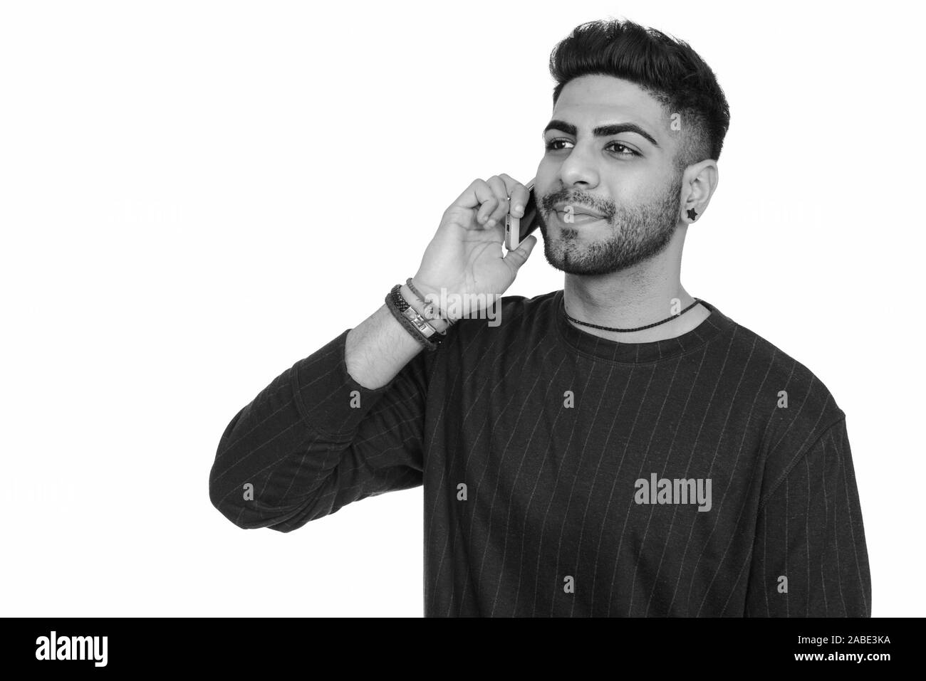 Studio shot of young happy Indian man talking on mobile phone isolated ...