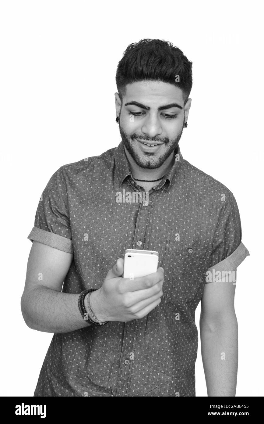 Studio shot of young happy Indian man using mobile phone isolated ...