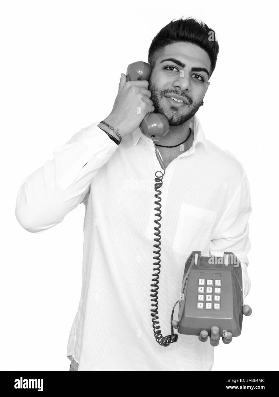 Studio shot of young happy Indian man talking on telephone isolated ...