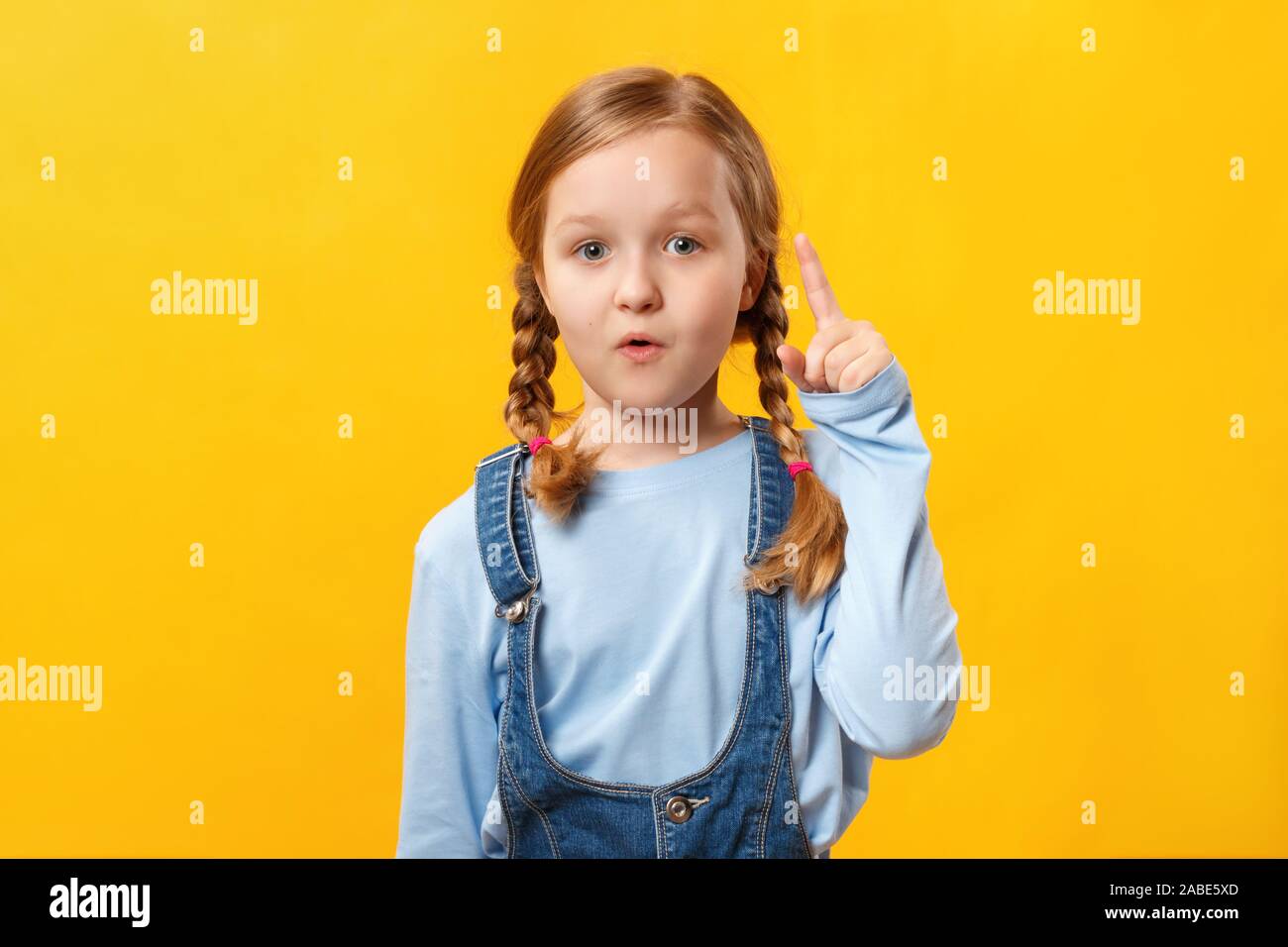 The little girl shows with index finger up on an empty place. The child ...