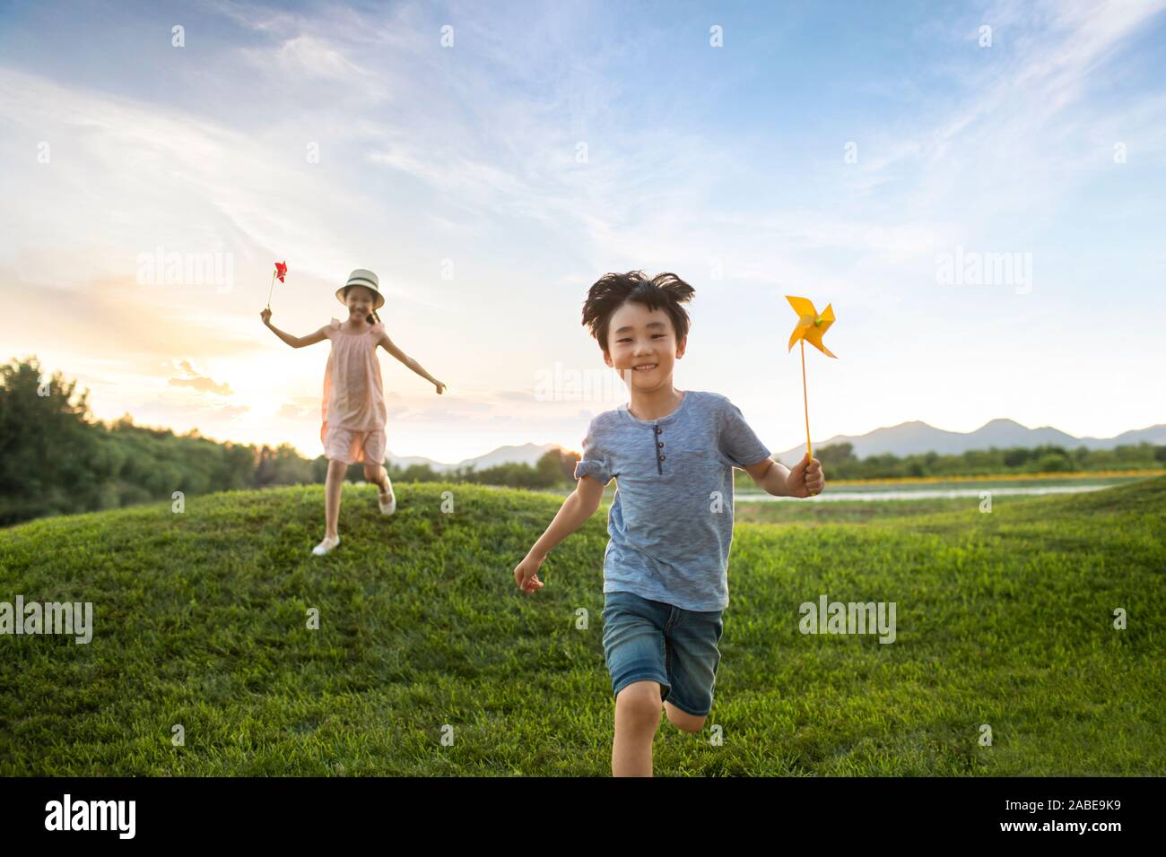 Two children playing paper windmill on meadow Stock Photo - Alamy
