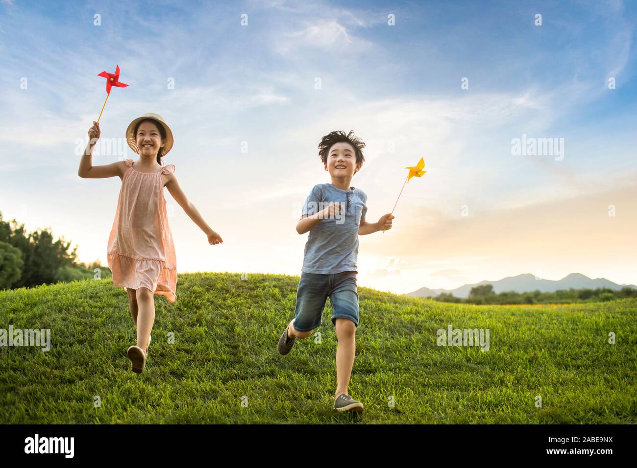 Two children playing paper windmill on meadow Stock Photo - Alamy