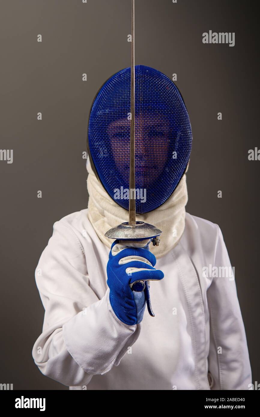 little boy fencer armed with a rapier in white sports equipment and ...