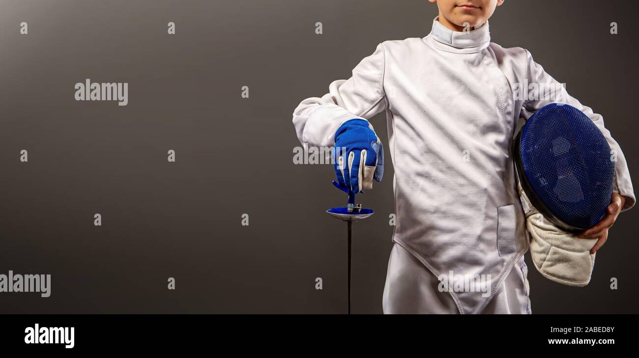 little boy fencer armed with a rapier in white sports equipment and ...