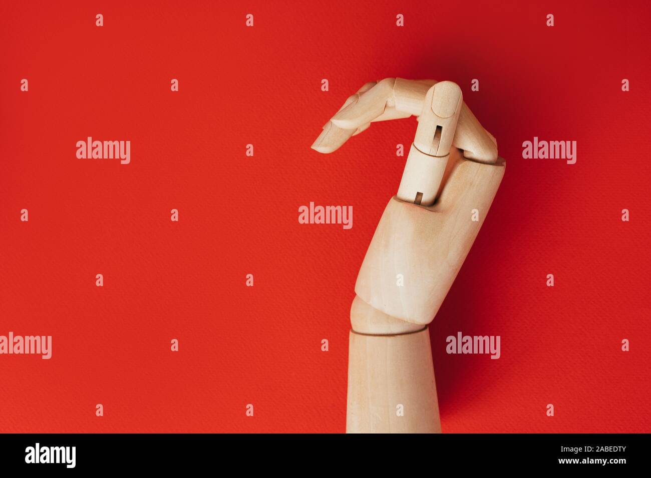 One wooden hand folded in the shape of a half heart on red background ...