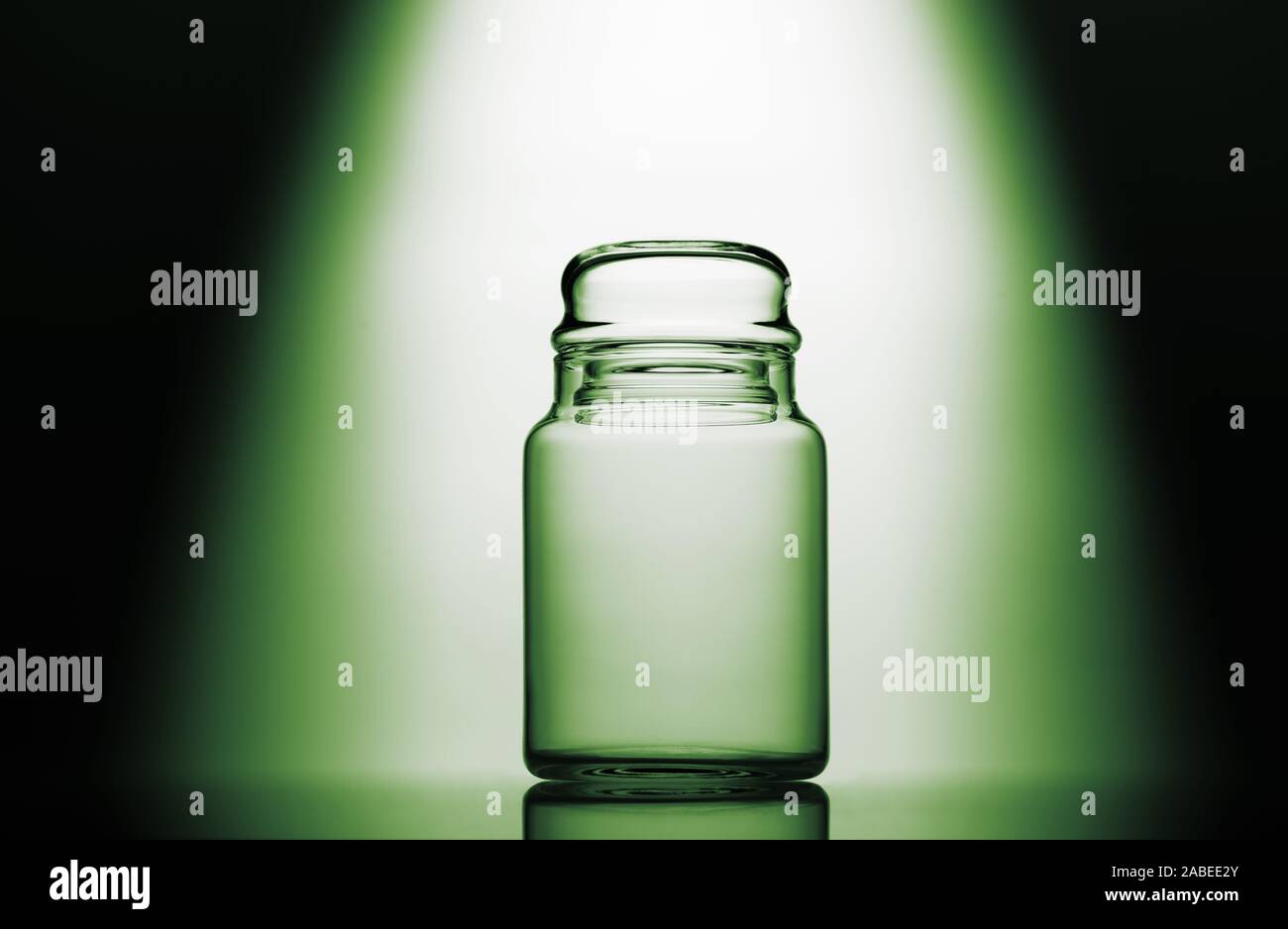 Empty glass jar on a green, black and white background with light ...