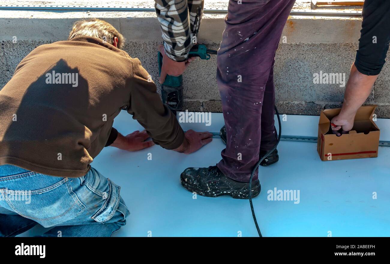 Worker with a heat gun is welding PVC sheets for waterproofing a ...