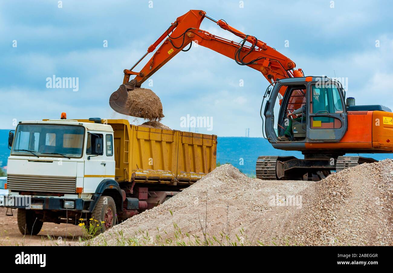 Loader excavator loads the ground in the truck at the road construction ...