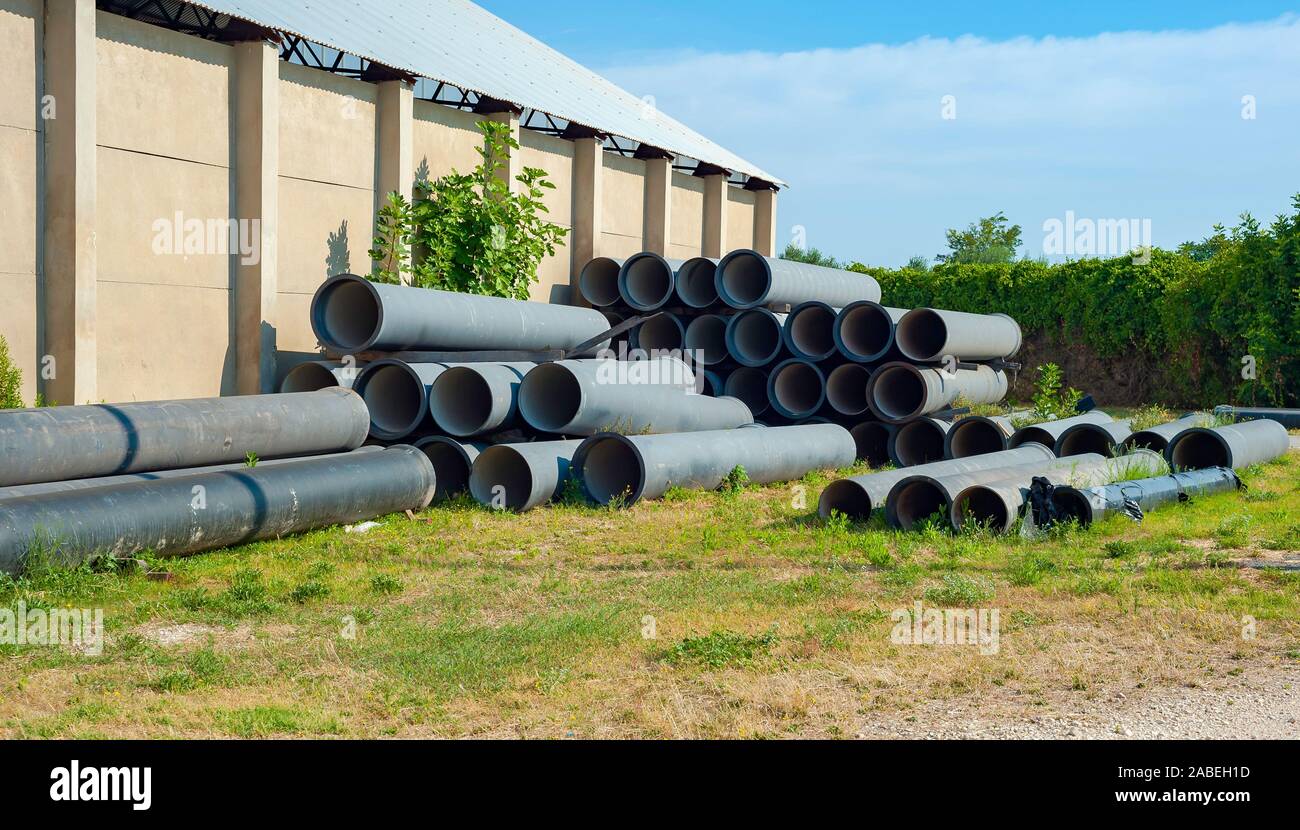 Stacks of blue PVC water pipes in stack on open storage at an factory ...