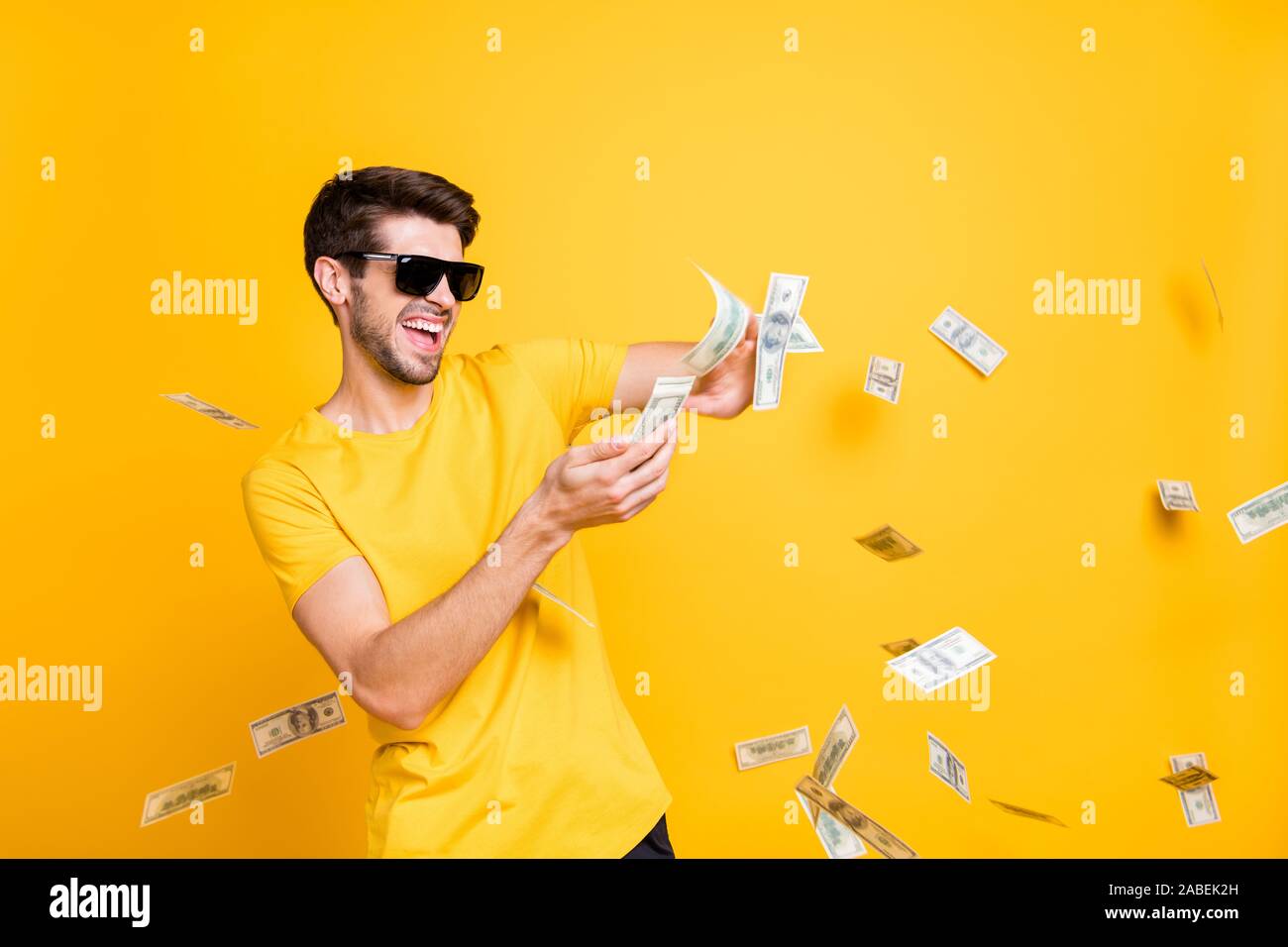 Photo of handsome careless generous guy throwing money banknotes away ...