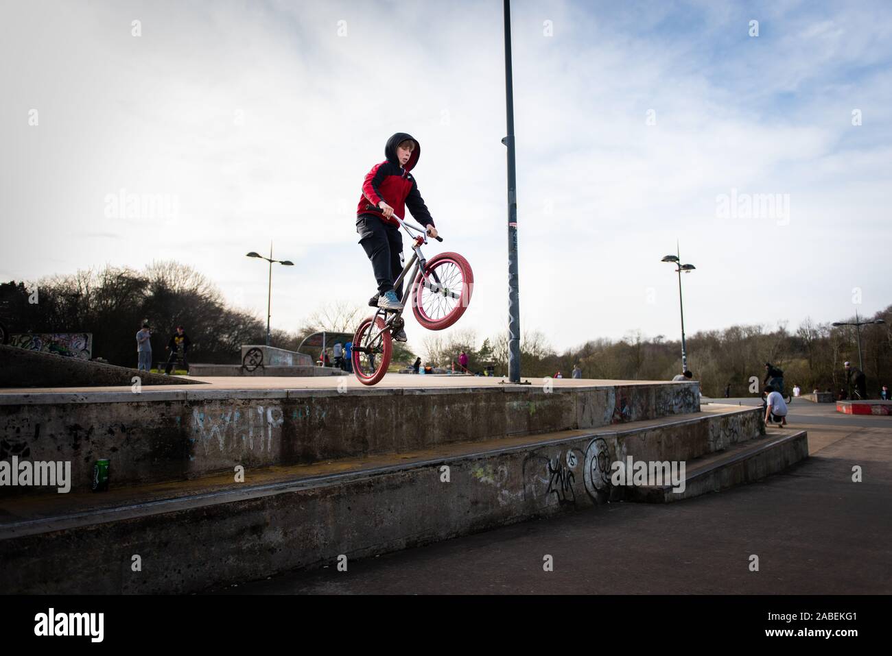 A young kid at the local skatepark practicing on his BMX, riding around ...