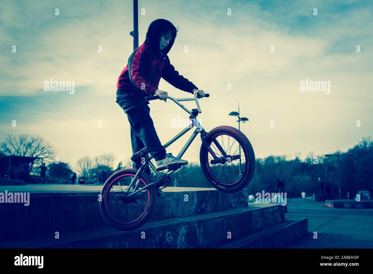 A young kid at the local skatepark practicing on his BMX, riding around ...