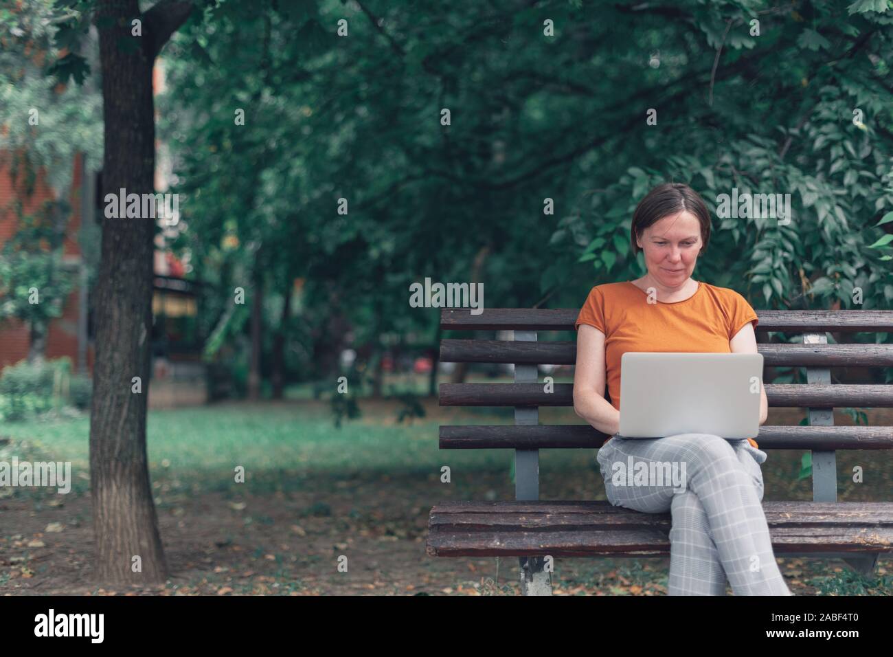 Woman using laptop computer on street bench,. Adult caucasian female ...