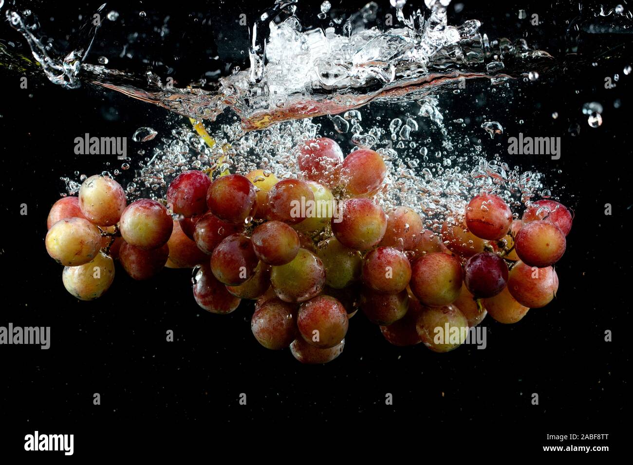 grape splashing into water in black background Stock Photo - Alamy