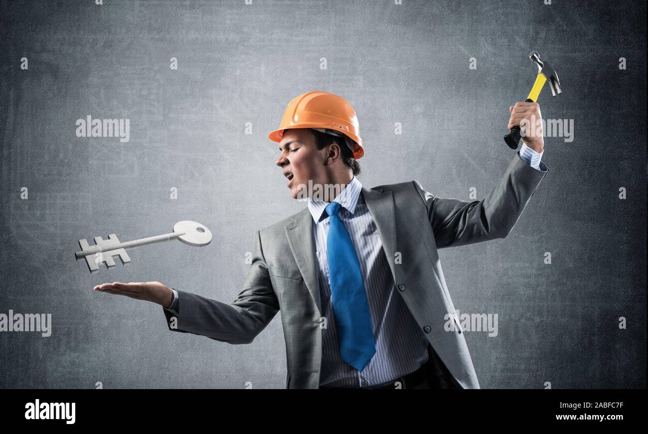 Businessman going to crash with hammer steel key Stock Photo - Alamy