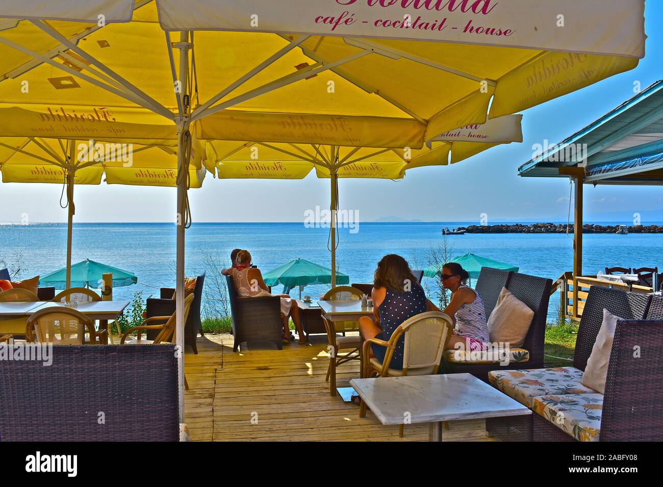 People relaxing in a beachfront café overlooking the sea, in the ...
