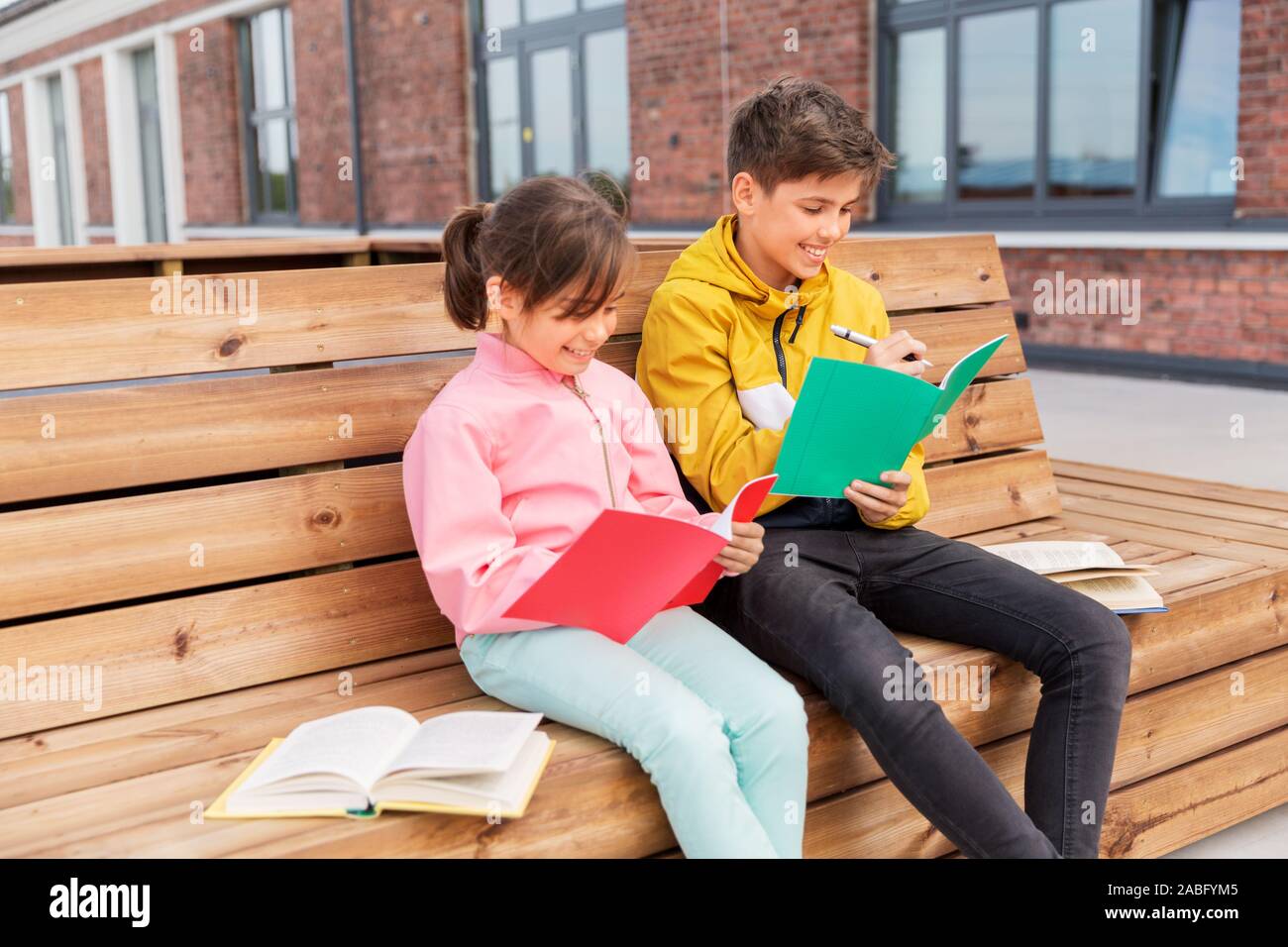 school children with notebooks sitting on bench Stock Photo - Alamy
