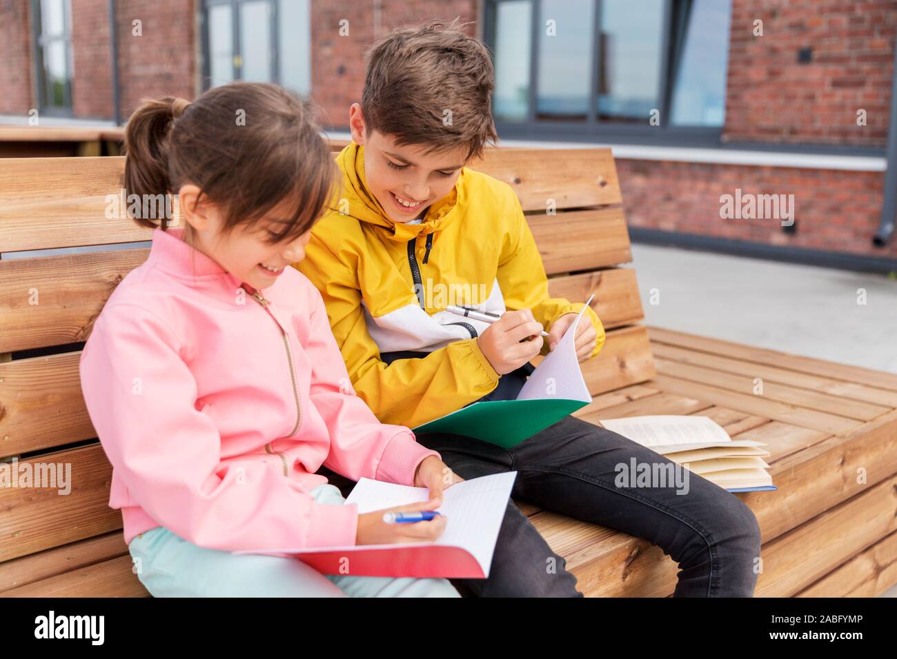 school children with notebooks sitting on bench Stock Photo - Alamy