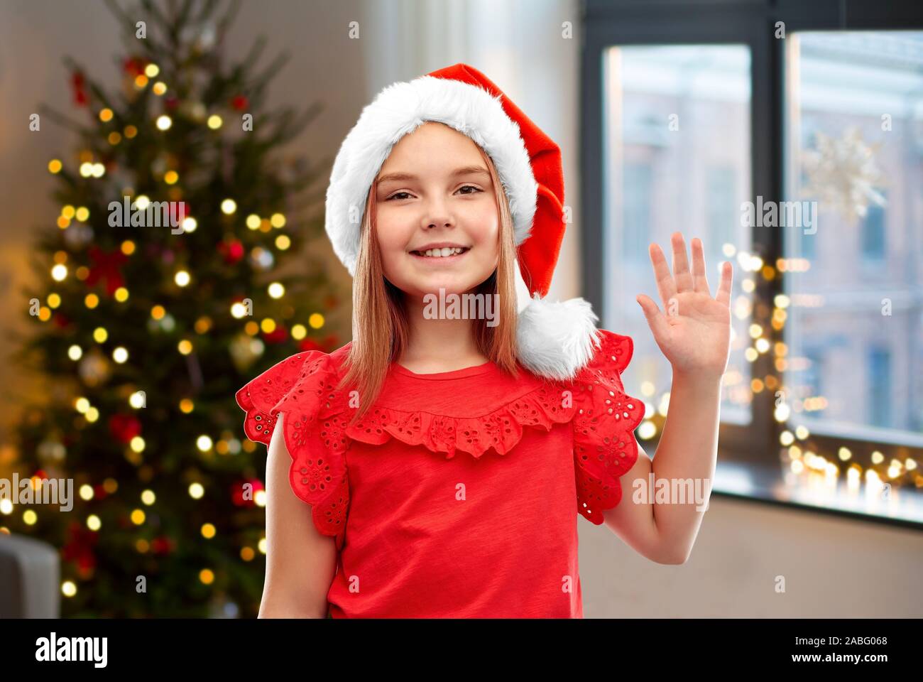 happy girl in santa helper hat waving hand at home Stock Photo - Alamy