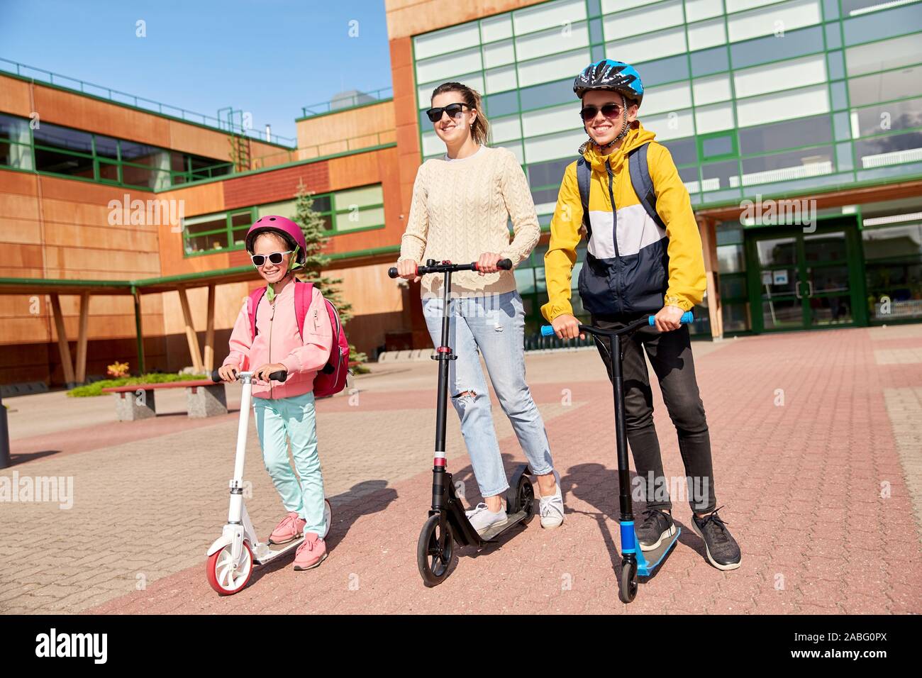 happy school children with mother riding scooters Stock Photo - Alamy
