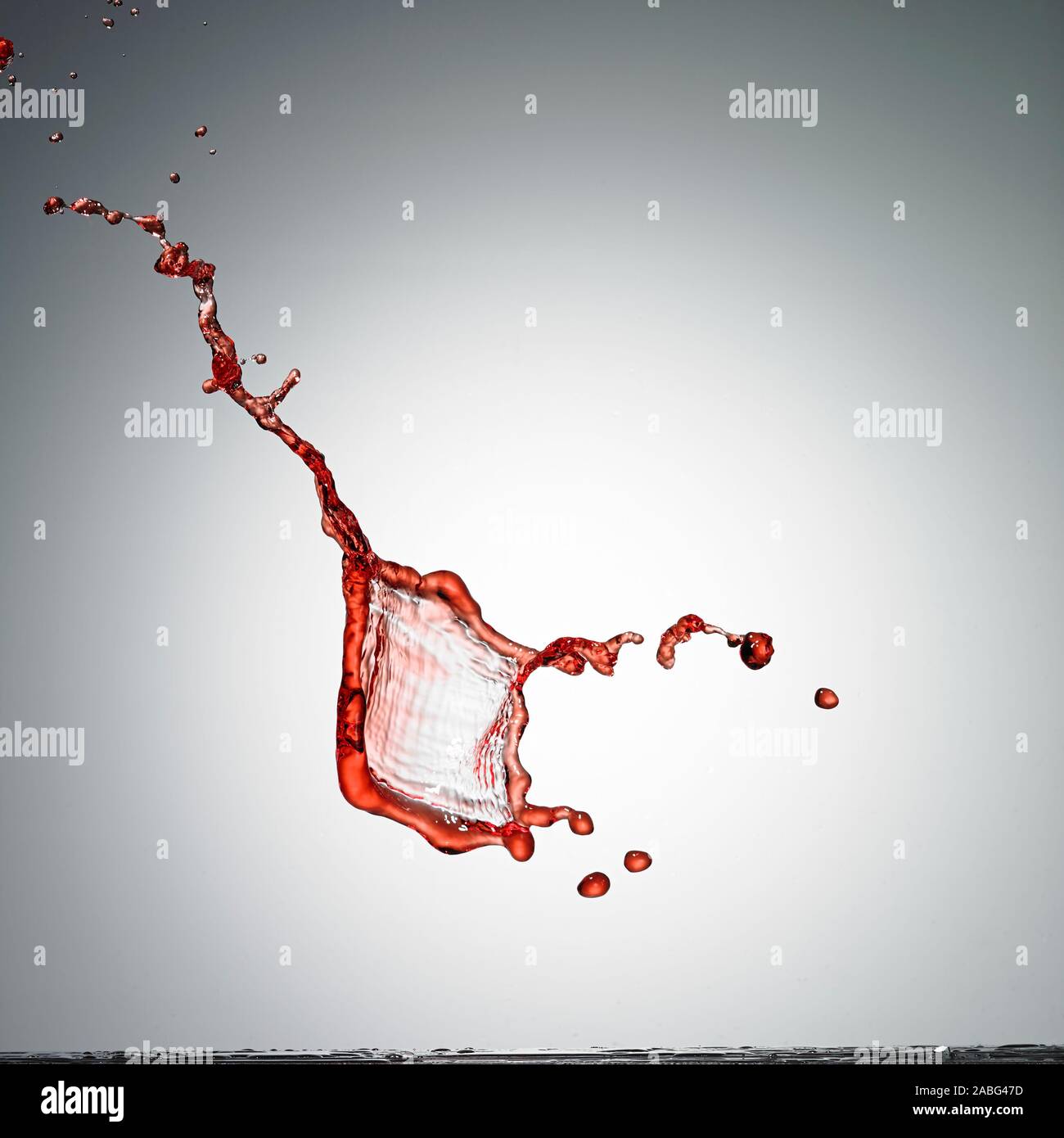 Red water splash shape on grey vignette background Stock Photo - Alamy