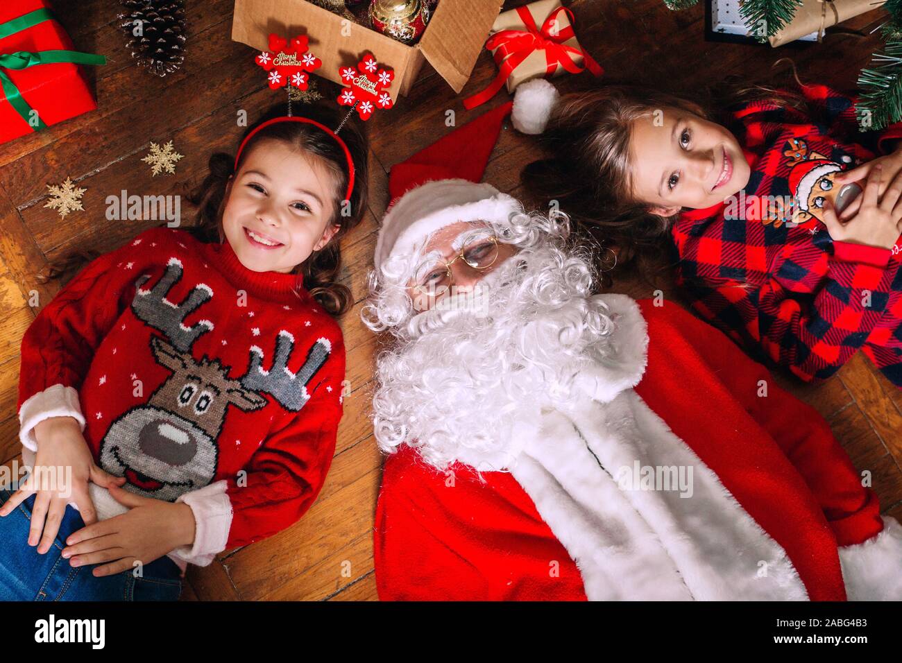 Two little girls and Santa Claus lie on the floor at home Stock Photo ...