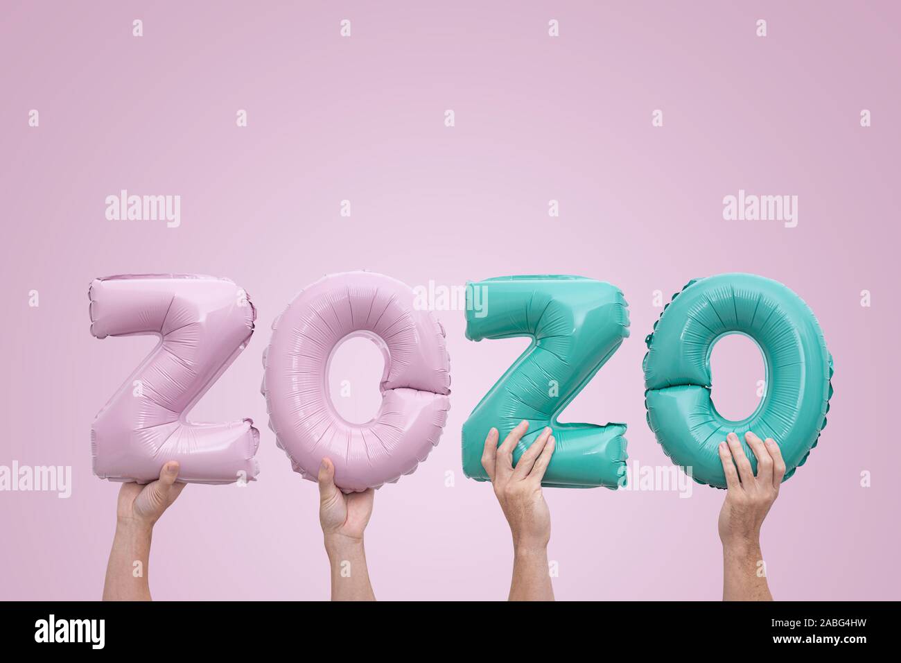 Hands holding numbers numbers 2020 made of pink and mint foil balloons ...