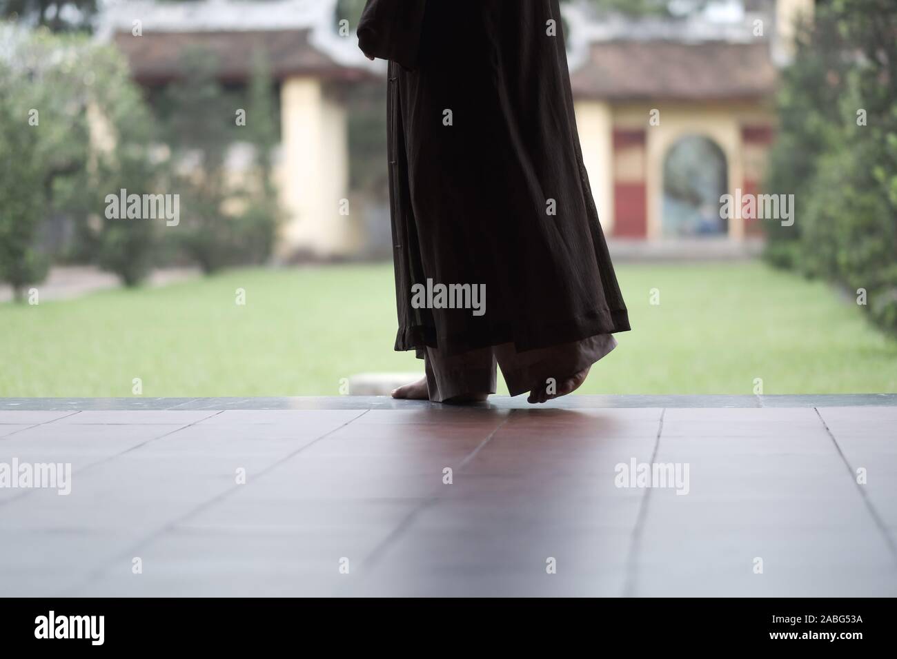 Buddhist monk's bare feet in traditional vestments, standing on the ...