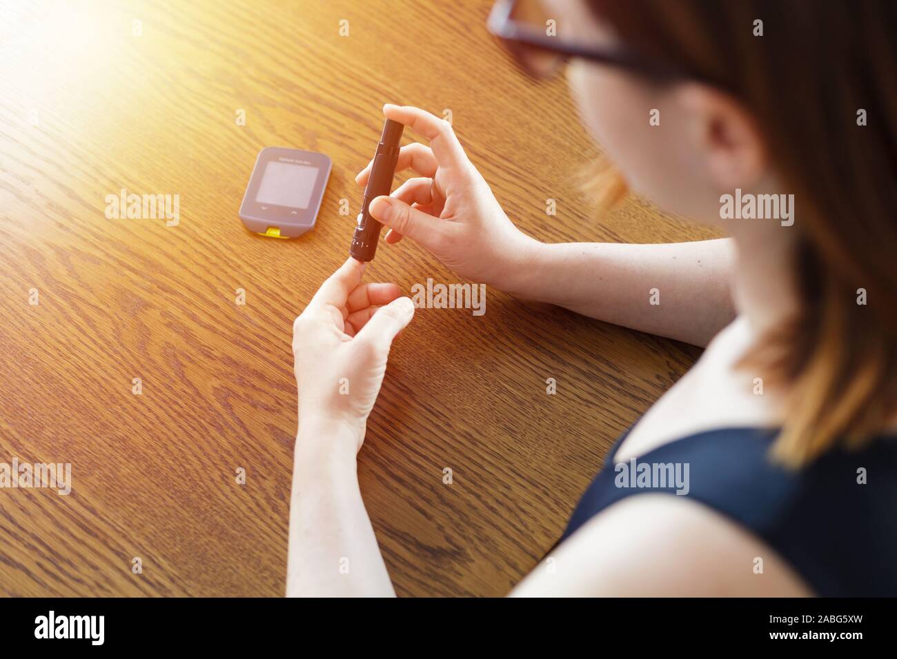 Woman using lancet to take blood sample to check glucose level with ...