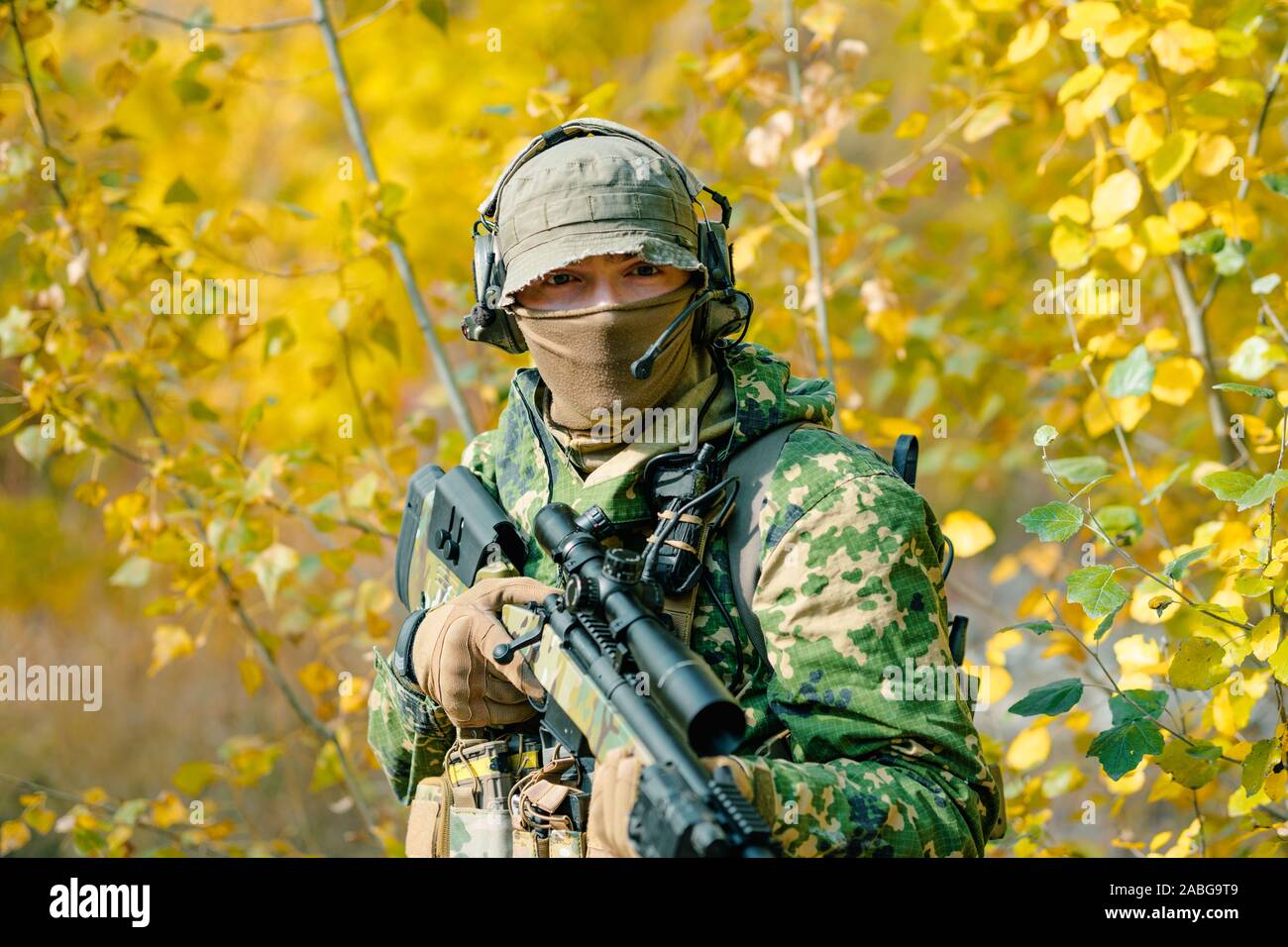 Closeup airsoft man in uniform, stand and hold sniper rifle on yellow ...