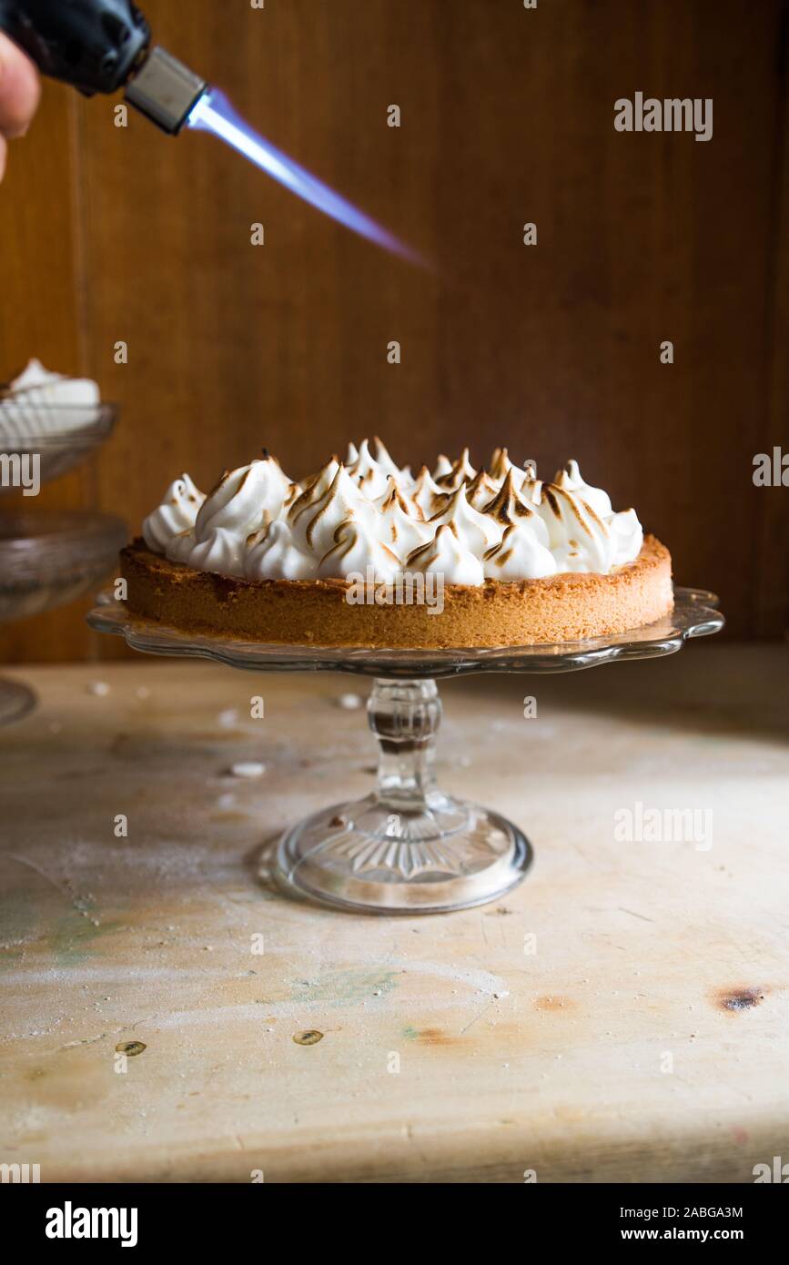 Lemon tart with french meringue caramelized on top, on a rustic table ...