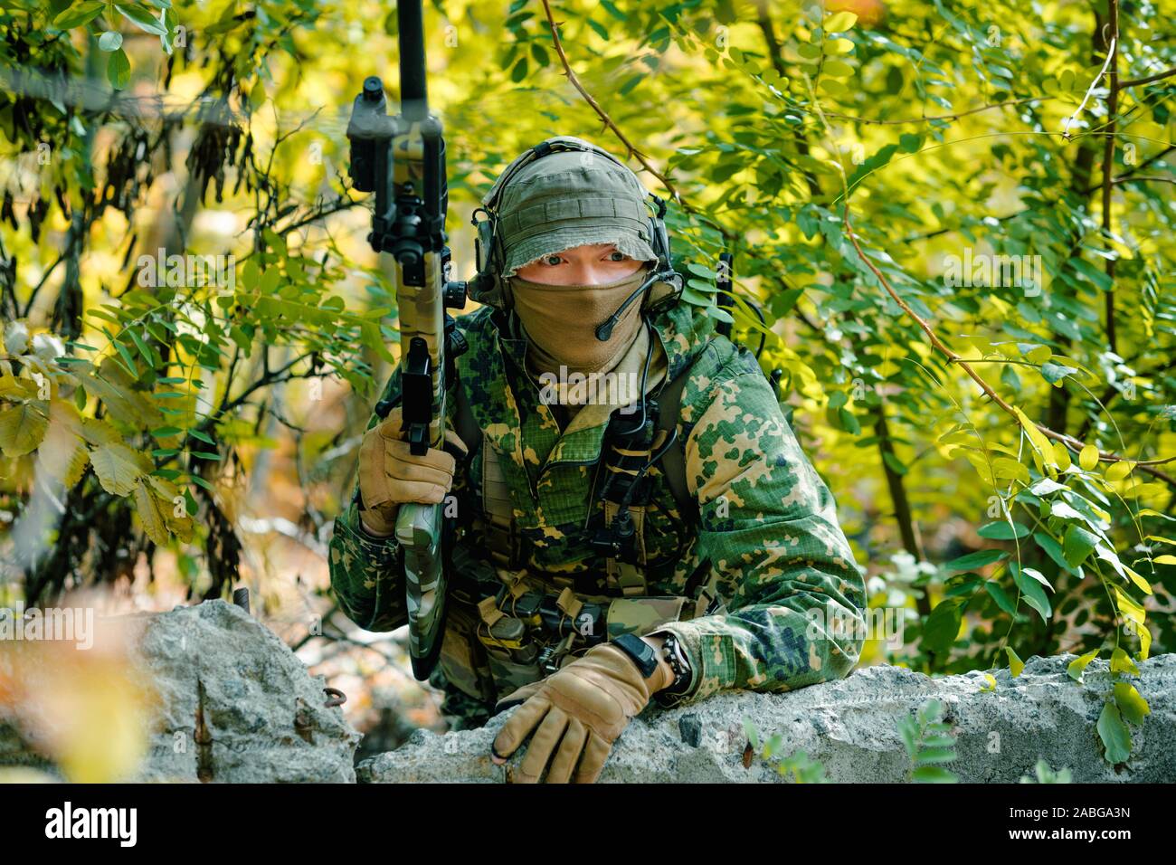 Airsoft man in uniform with machine gun and night-vision device on ...