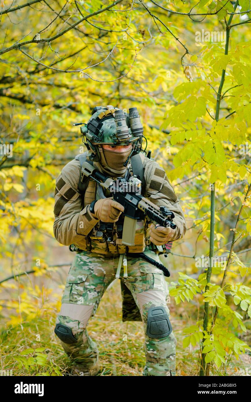 Airsoft man in uniform with machine gun and night-vision device on ...