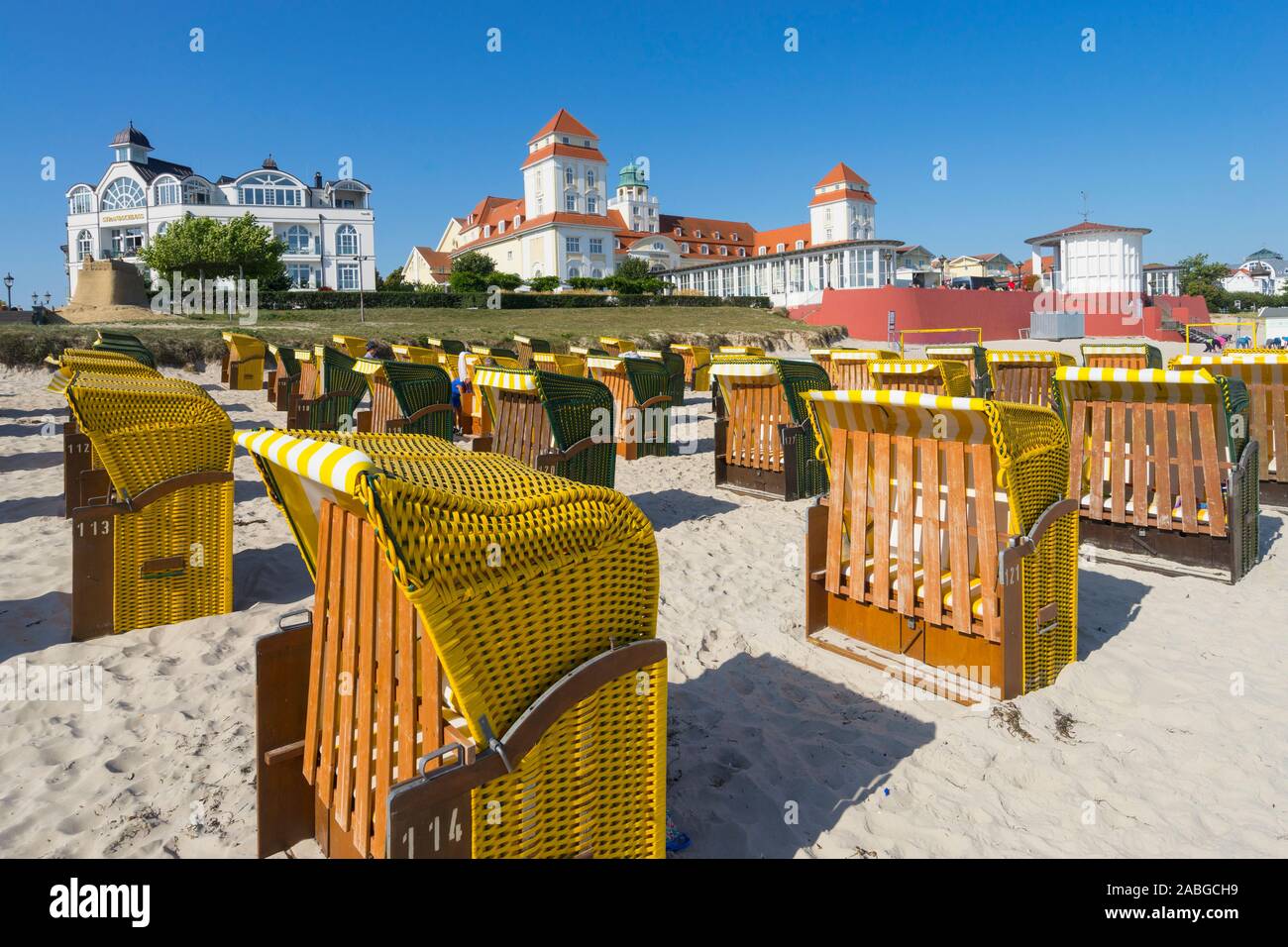 View of traditional Strandkorb chairs on beach and Kurhaus Binz Hotel ...