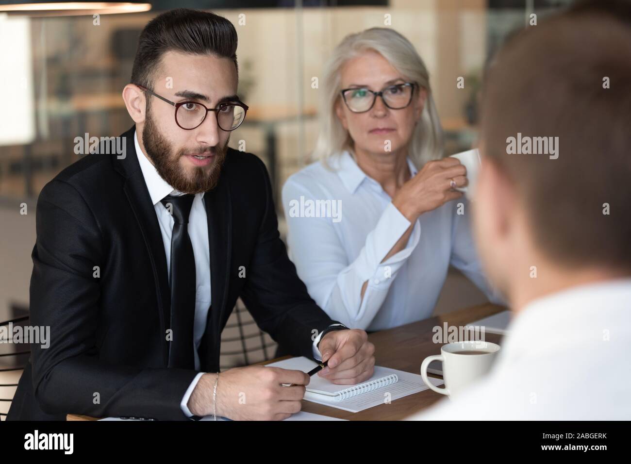 Multiracial employers talk with male applicant at interview Stock Photo ...