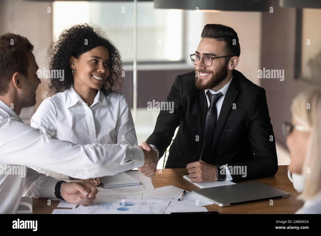 Smiling male colleagues handshake greeting at office briefing Stock ...