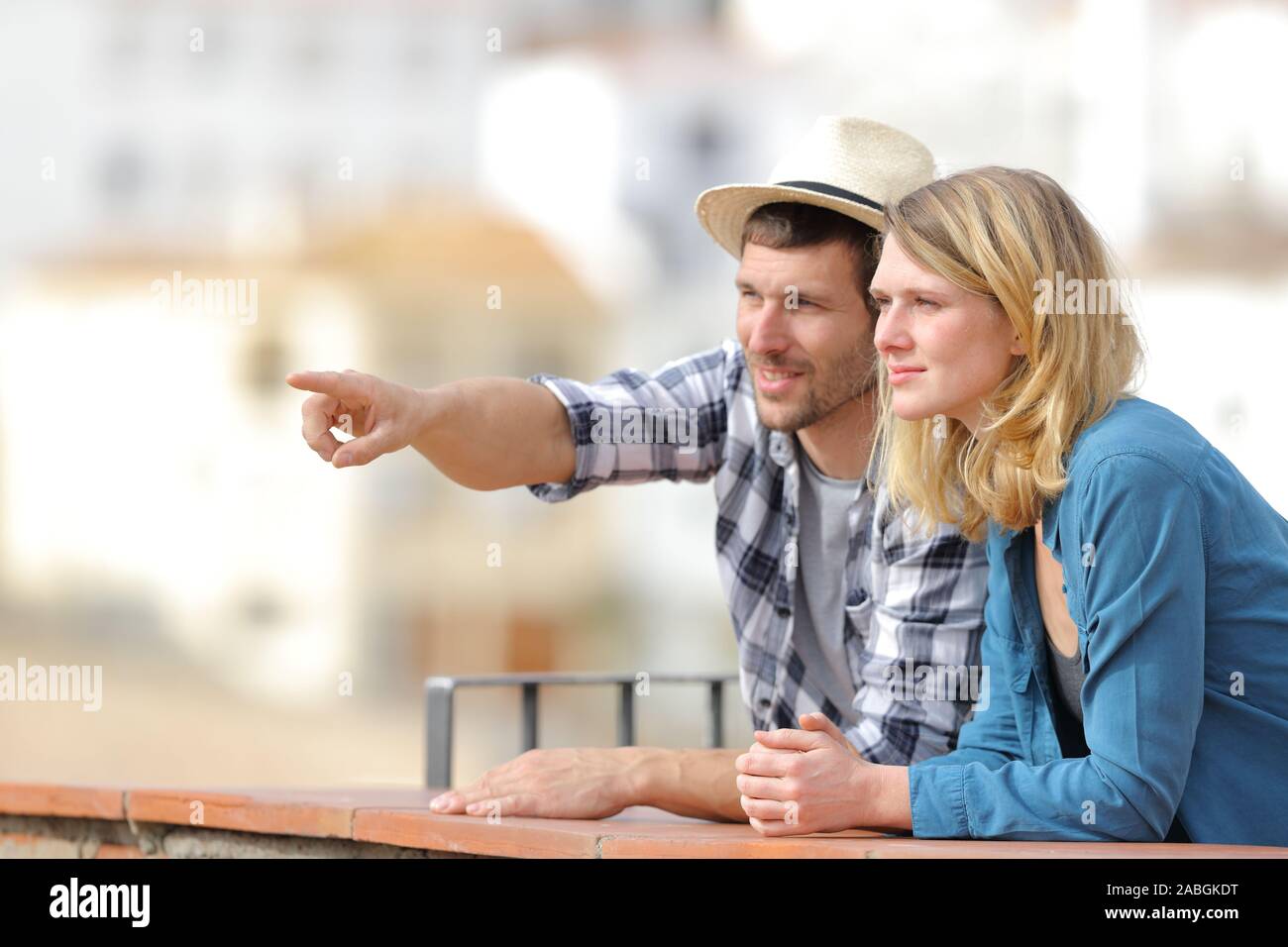 Couple of tourists sightseeing pointing at horizon standing outdoors in ...